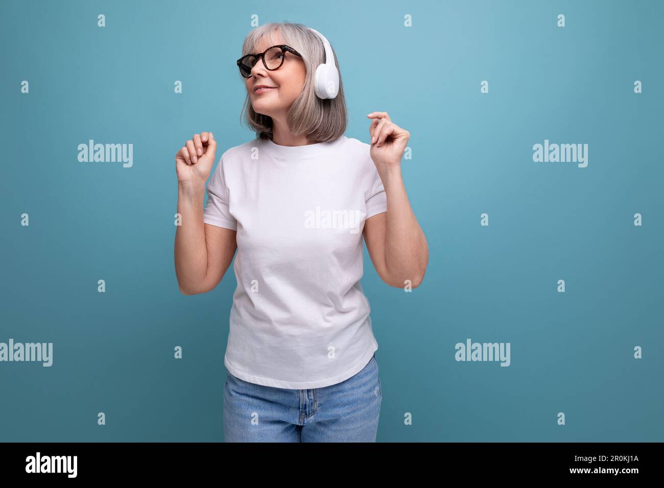 modern grandmother with gray hair listens to music in wireless ...