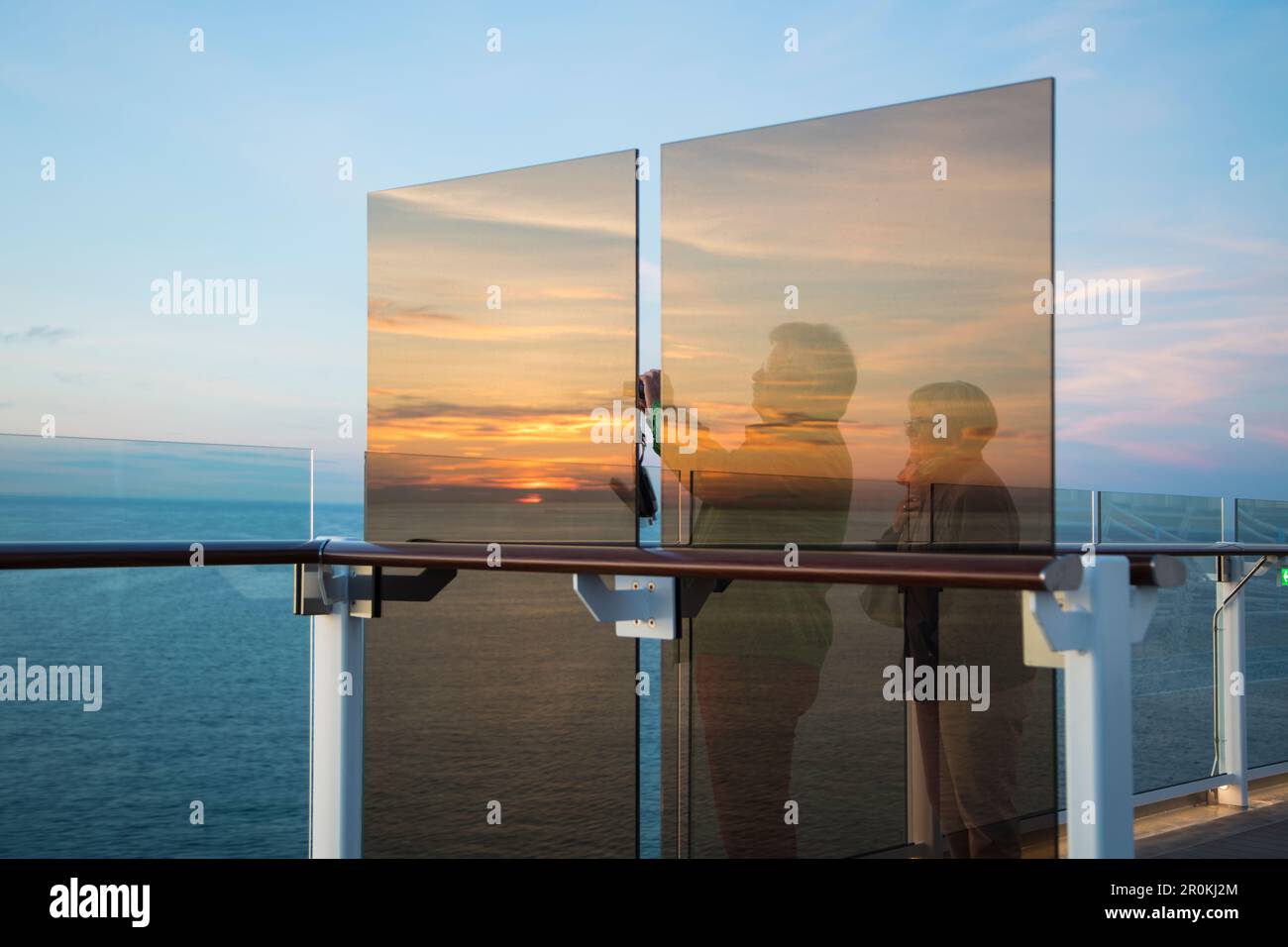 Couple photographs sunset from behind wind break window on Deck 14 ...