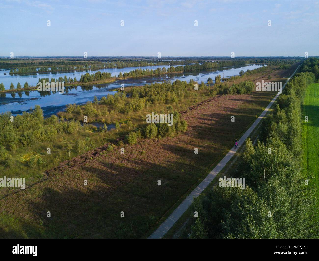 Aerial of people cycling along lakes and peat bog lands through ...