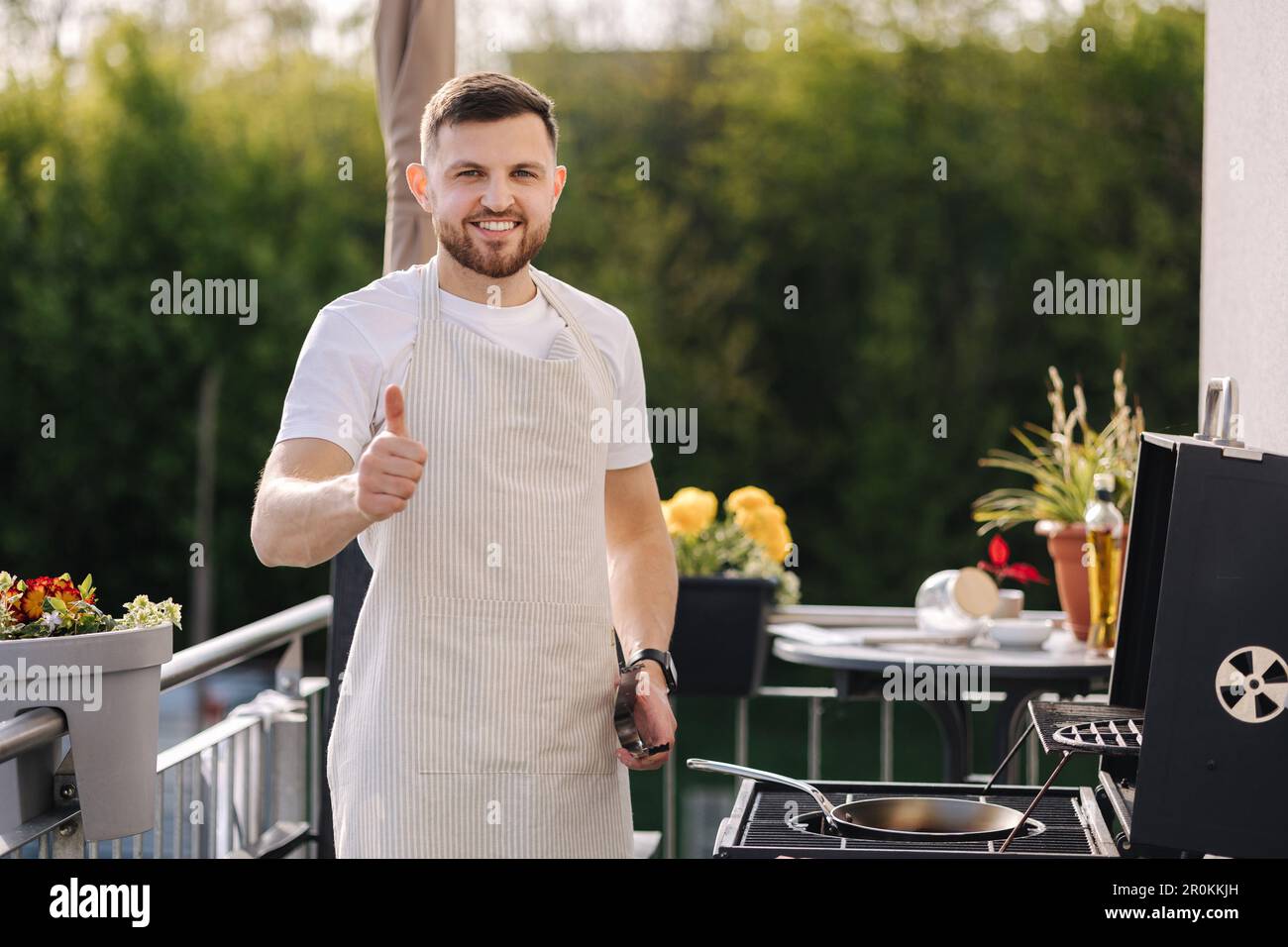 Portrait of handsome young chief in apron stand by the BBQ grill and ...