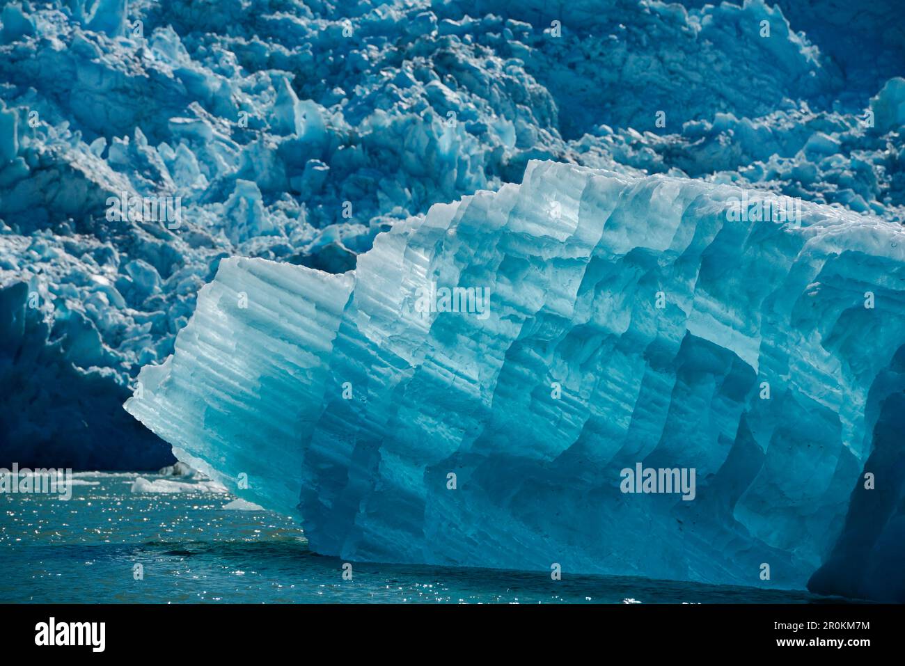 A large iceberg of translucent ice floats in front of the Sawywer ...
