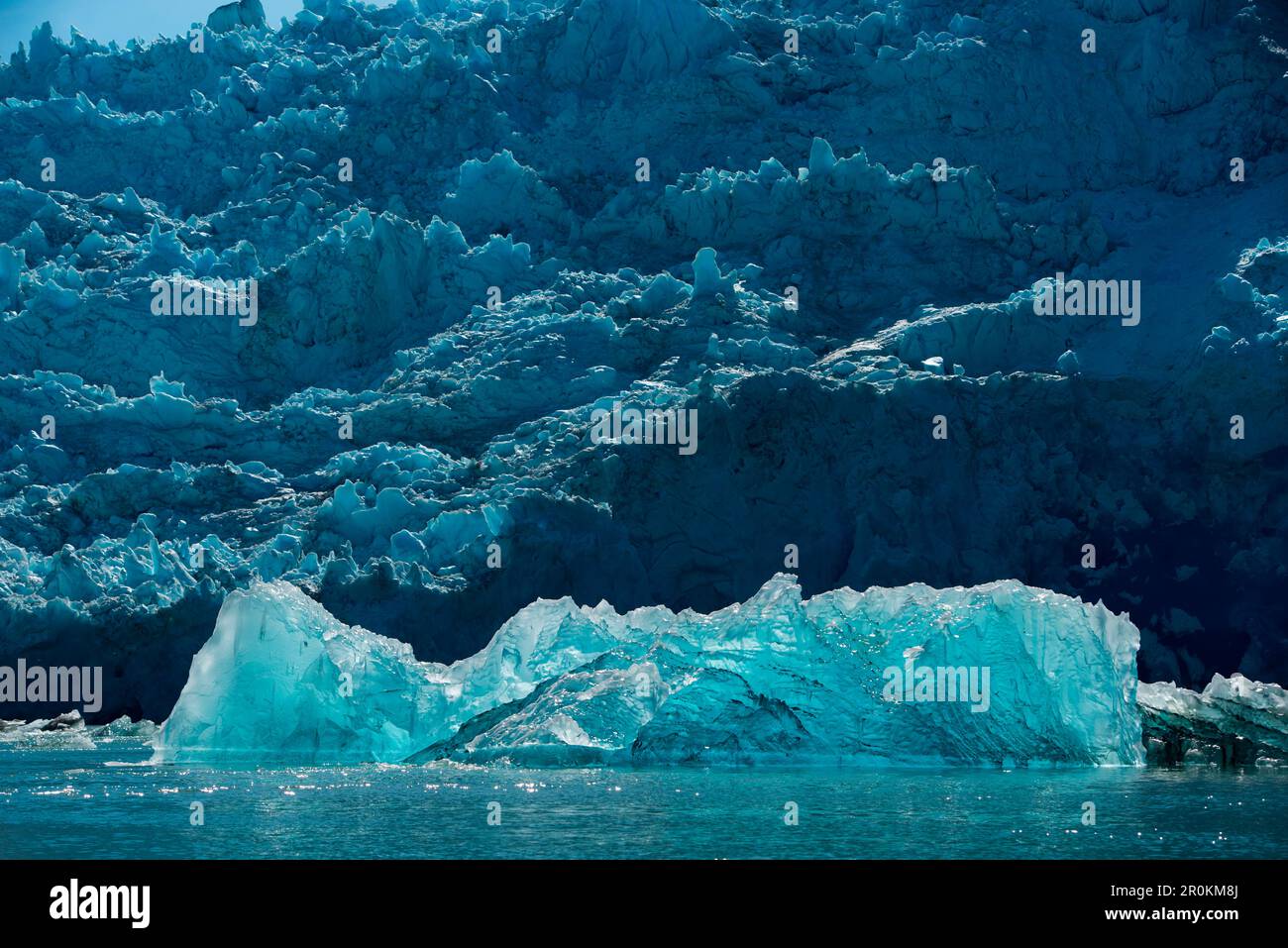 A large iceberg of translucent ice floats in front of the Sawywer ...
