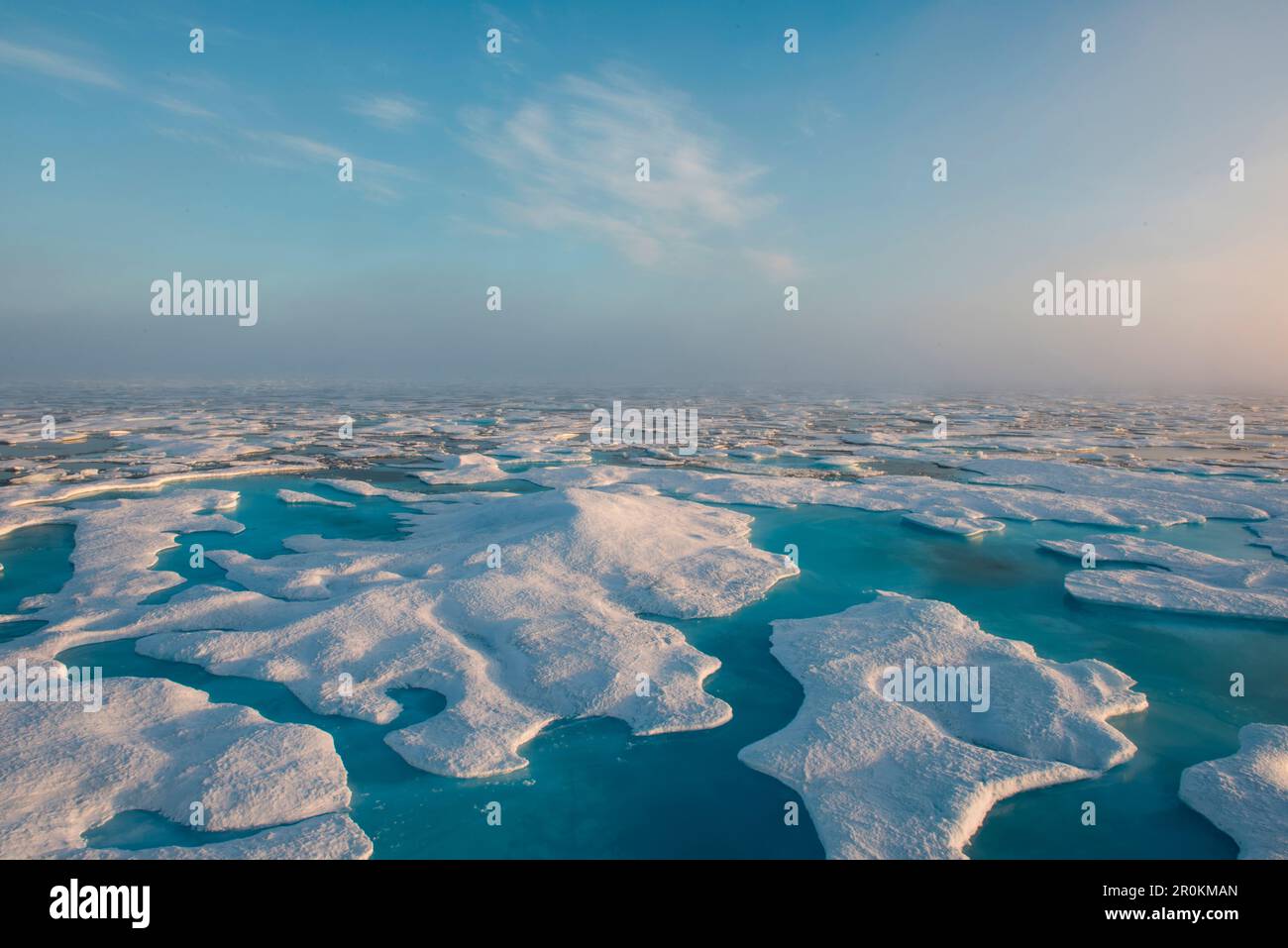 Blue skies and a sea of ice with turquoise-blue pools of water, making ...