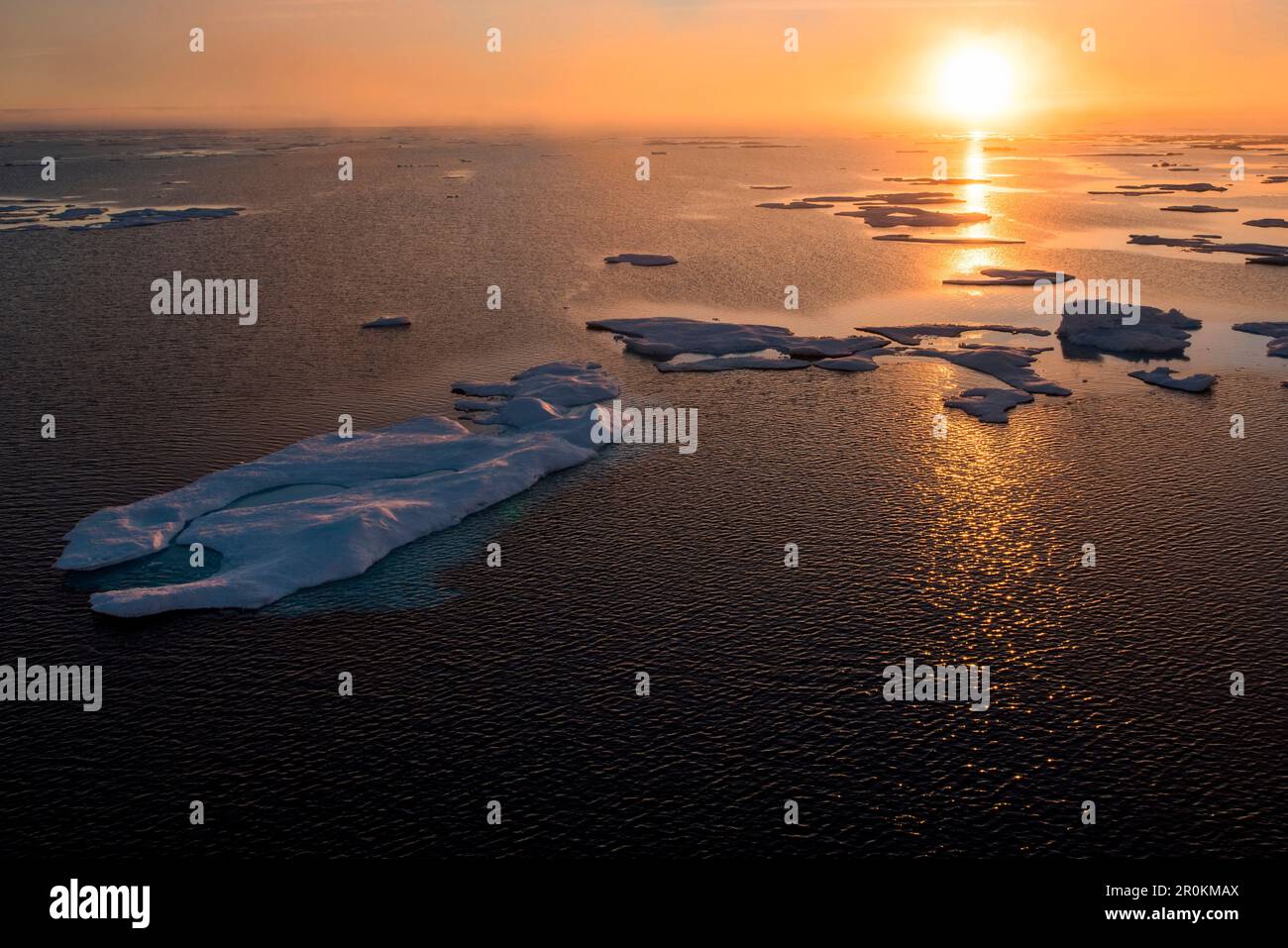 A golden sun rises over chunks of ice, near Prince of Wales Island ...