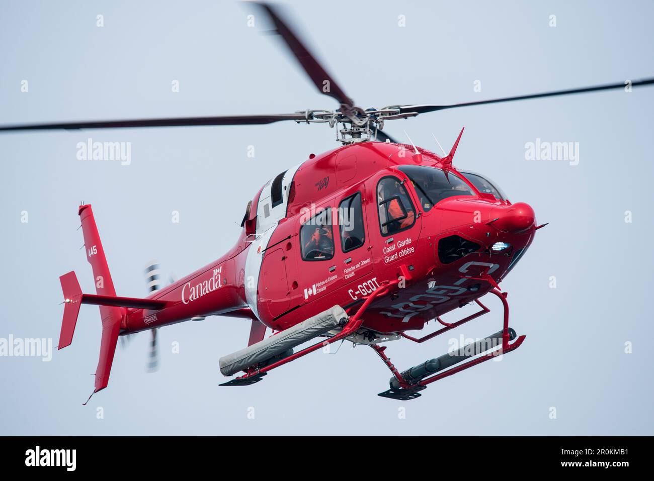 A red Canadian Coast Guard helicopter flies against an overcast sky ...