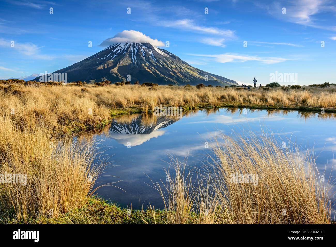 Vulcano Mount Egmont reflecting in lake, person standing in background ...