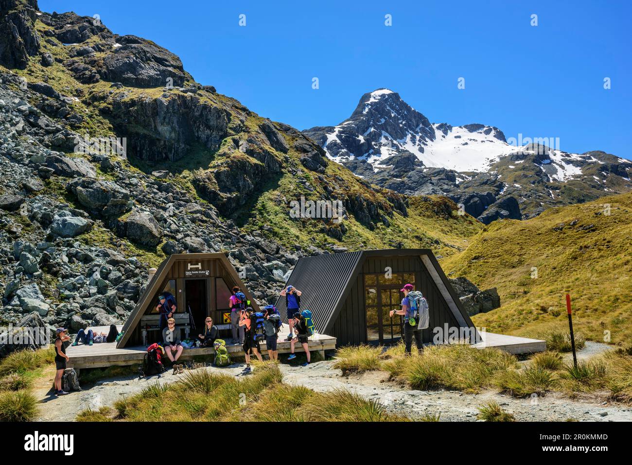 Several persons standing in front of shelter huts at Harris Saddle ...