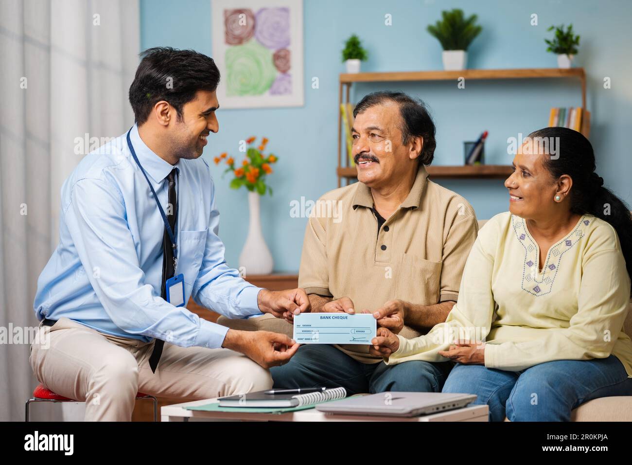 Happy indian banker giving cheque to senior couple at home - concept of ...