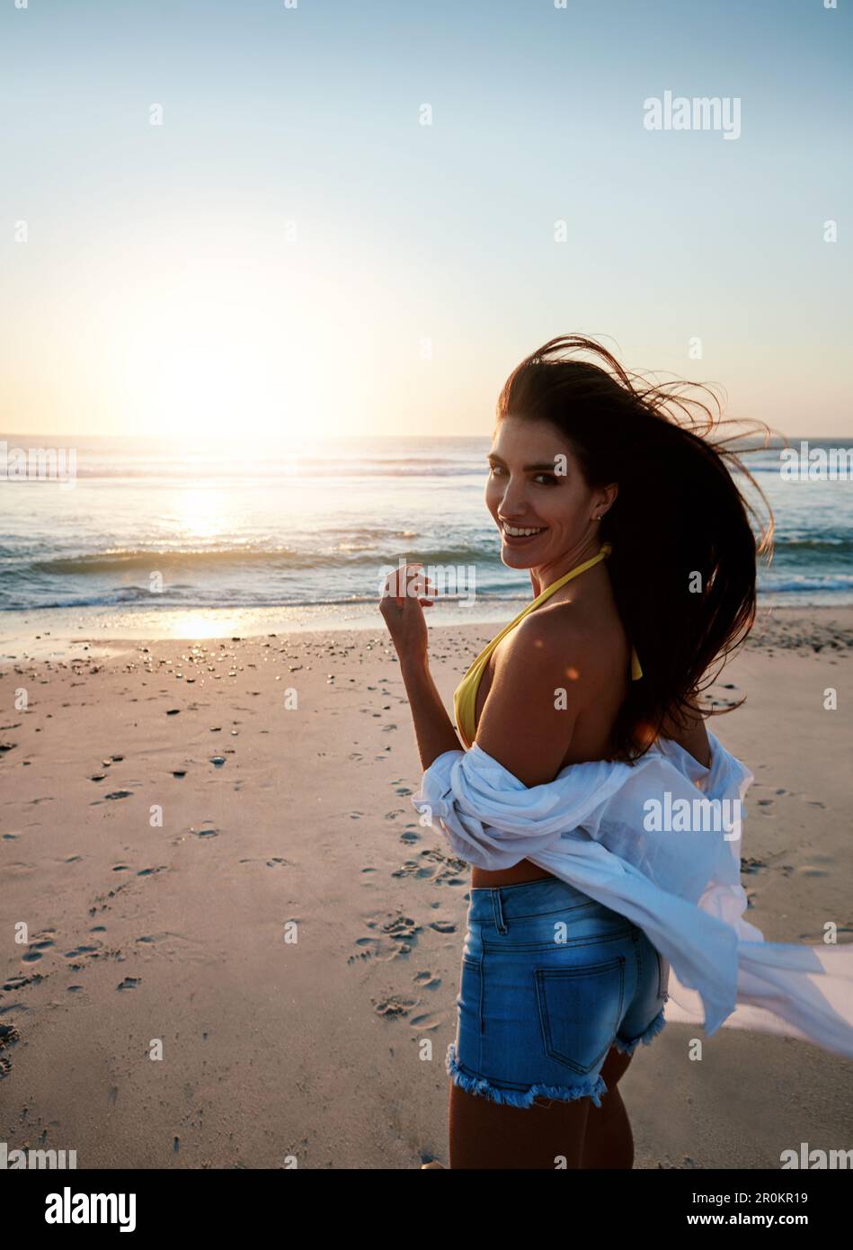 The sunset is as beautiful as she is. a beautiful young woman enjoying ...