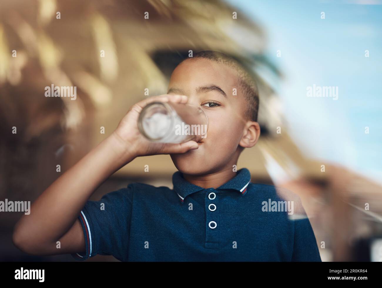 I need some water. a young boy drinking a glass of water at home Stock ...