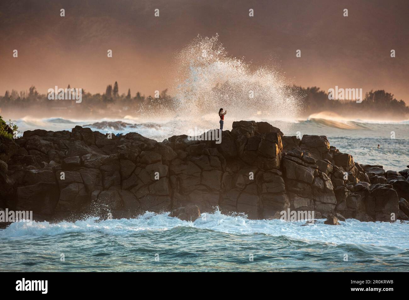 HAWAII, Oahu, North Shore, individuals out on the rocks watching the ...