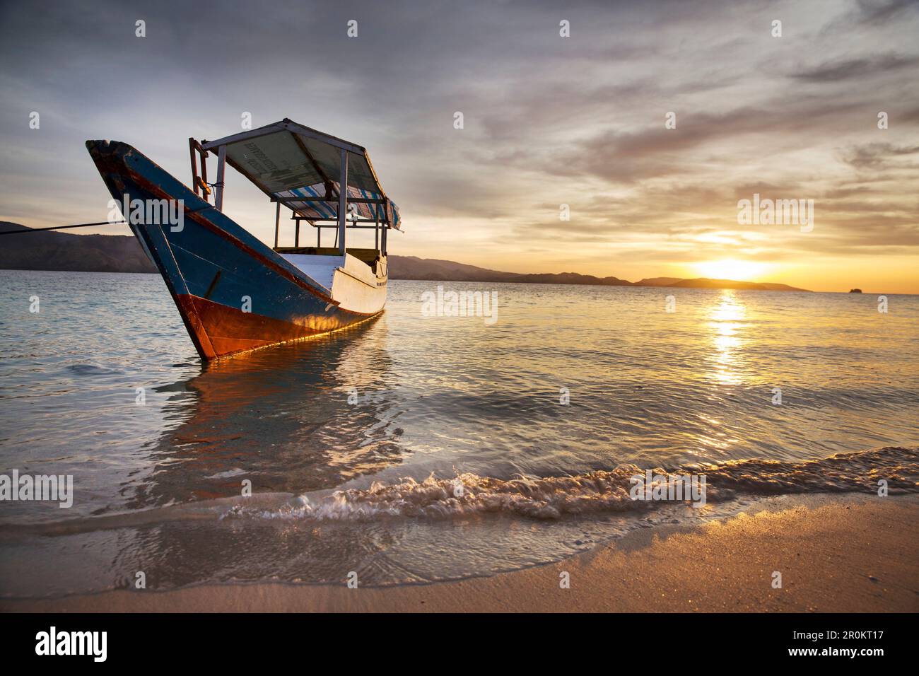 INDONESIA, Flores, Riung, a boat floats in the Flores Sea at sunset on ...