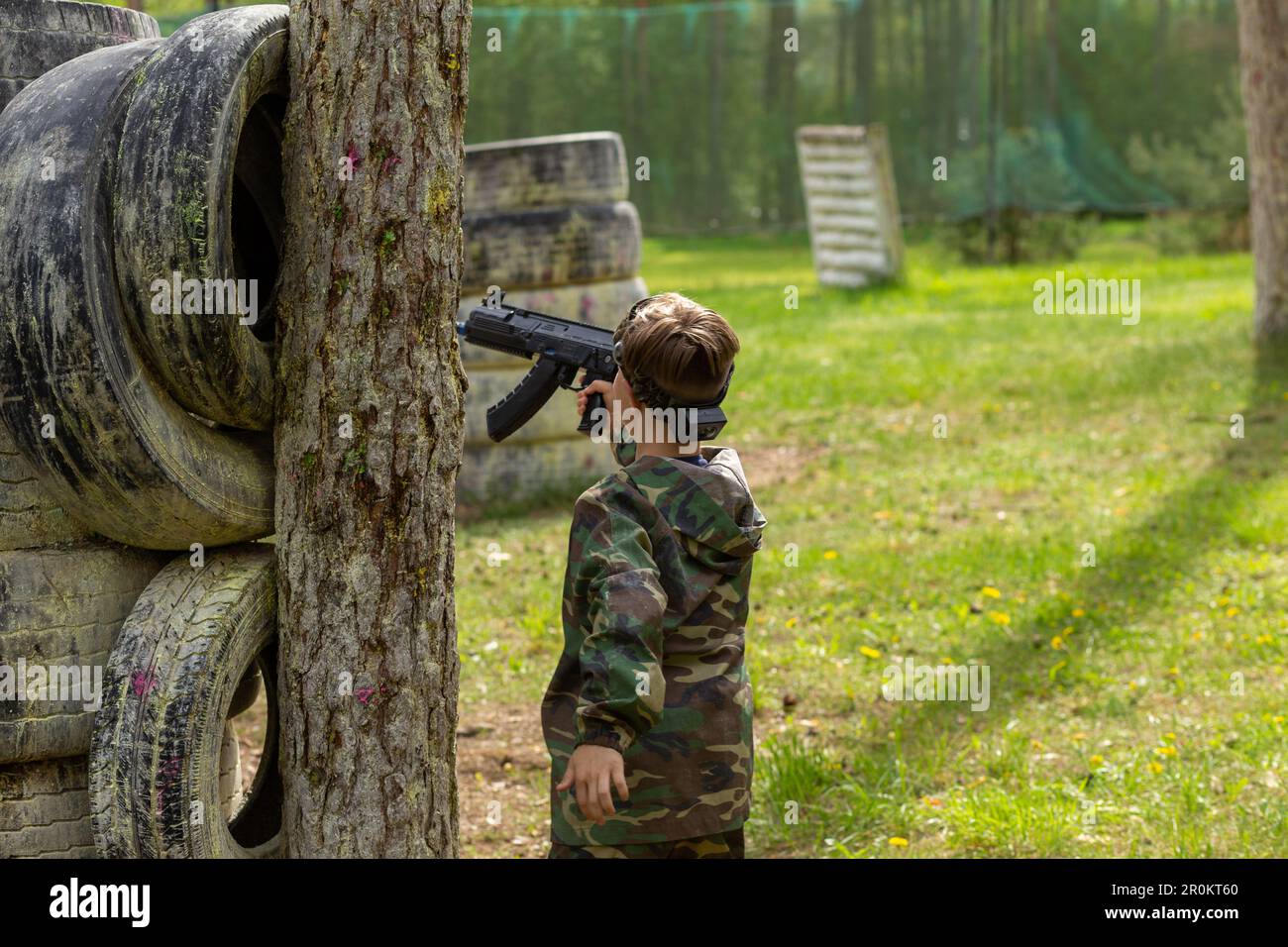 Boy weared in camouflage playing laser tag in special forest playground ...