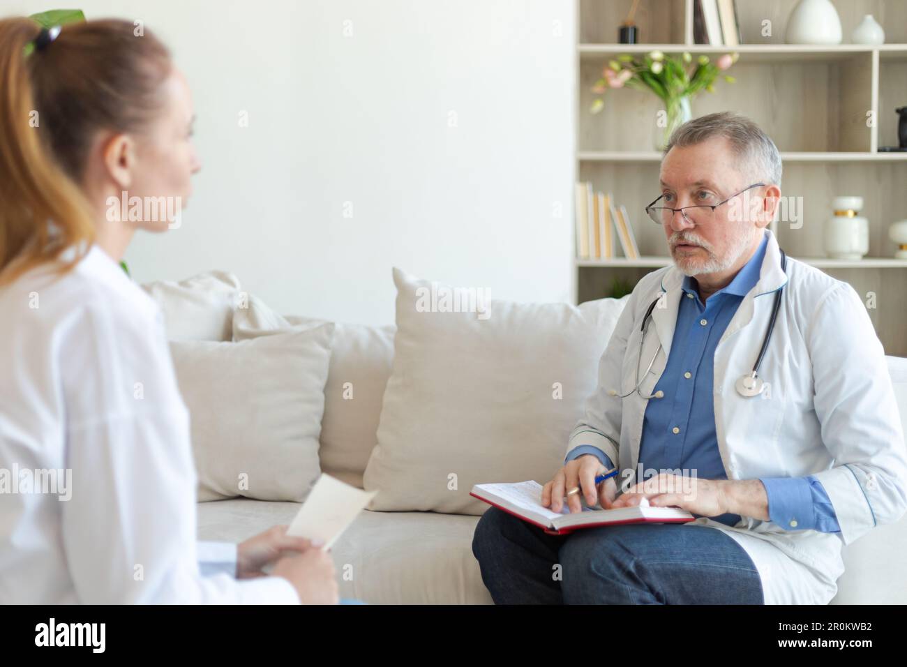 Senior man doctor examining yound woman in doctor office or at home ...