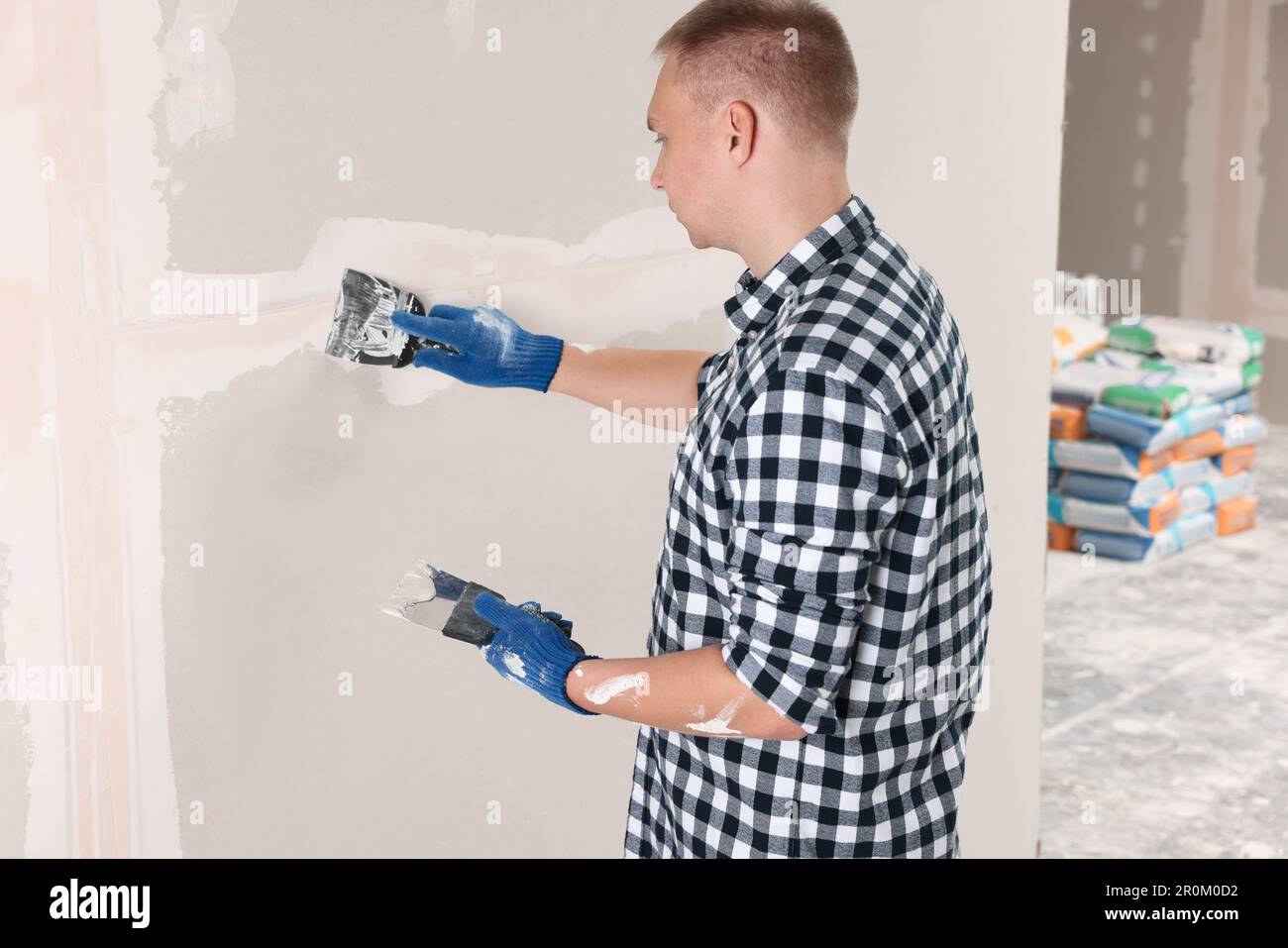 Man plastering wall with putty knife indoors. Home renovation Stock ...
