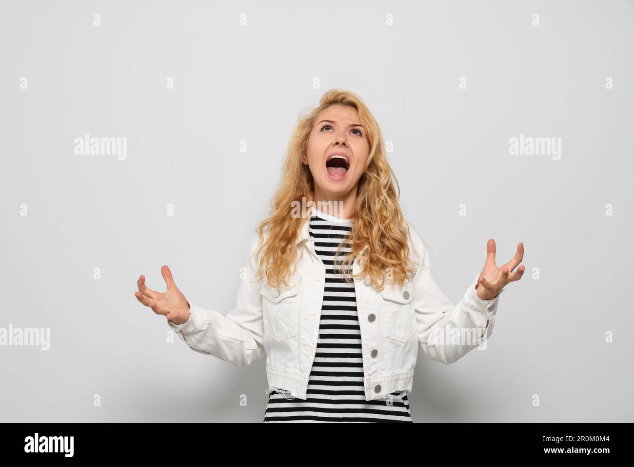 Aggressive young woman screaming with rage on white background Stock ...