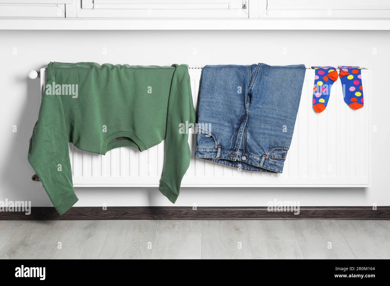 Clothes hanging on white radiator in room Stock Photo - Alamy