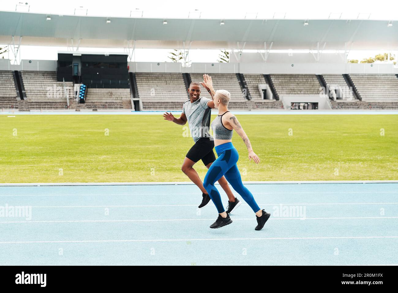 Great job. Full length shot of two young athletes giving each other a ...