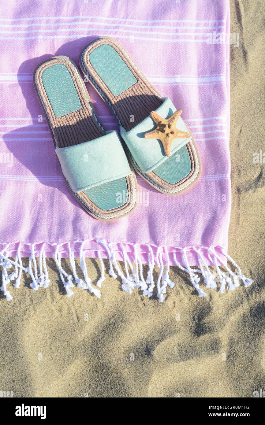 Pink blanket with stylish slippers and dry starfish on sandy beach, top ...