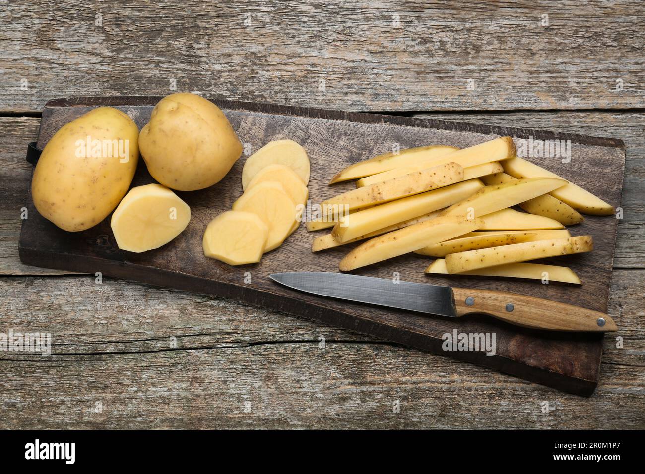 Whole and cut potatoes with knife on wooden table, top view. Cooking ...