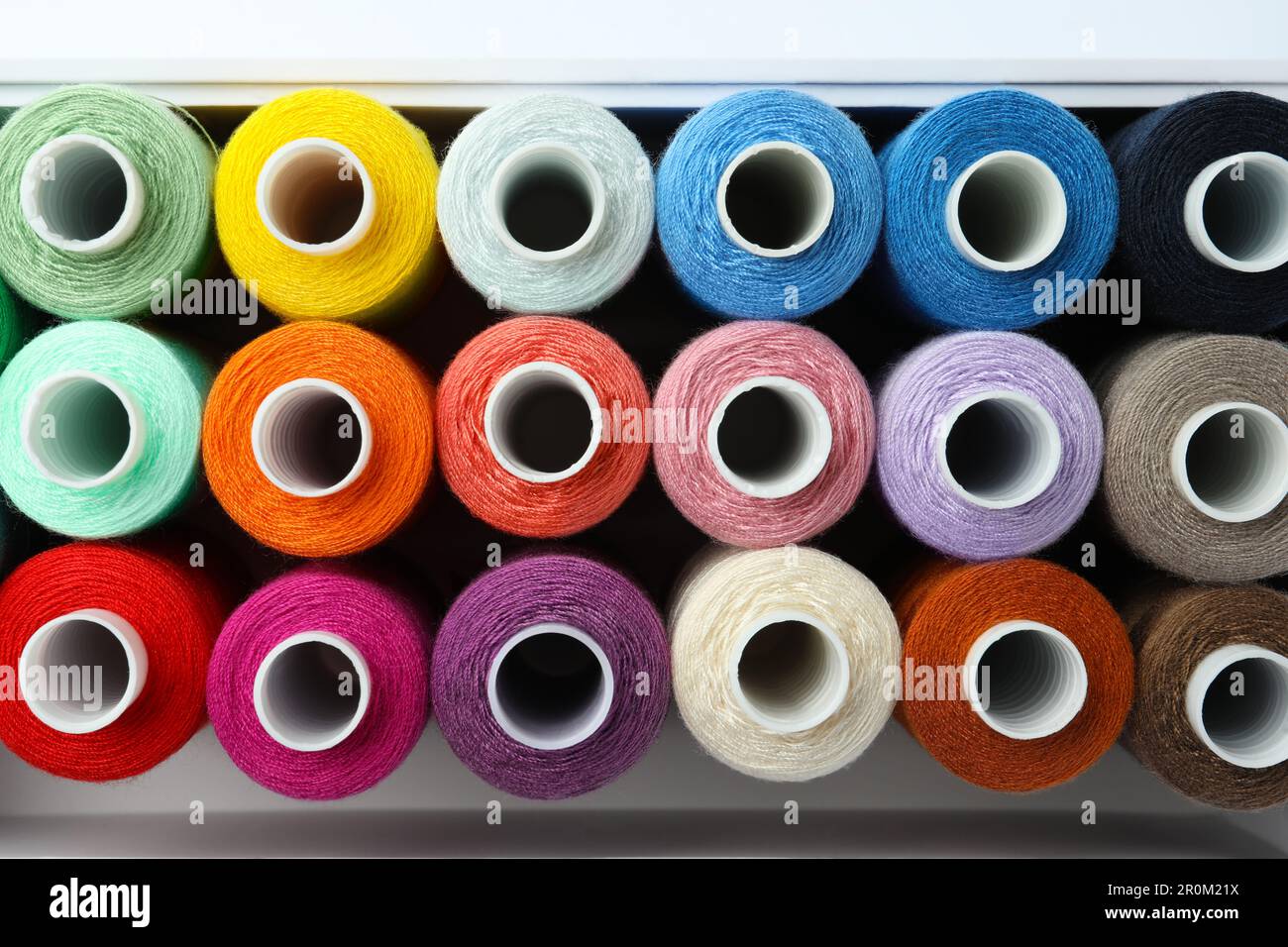 Set of different colorful sewing threads in container on white ...