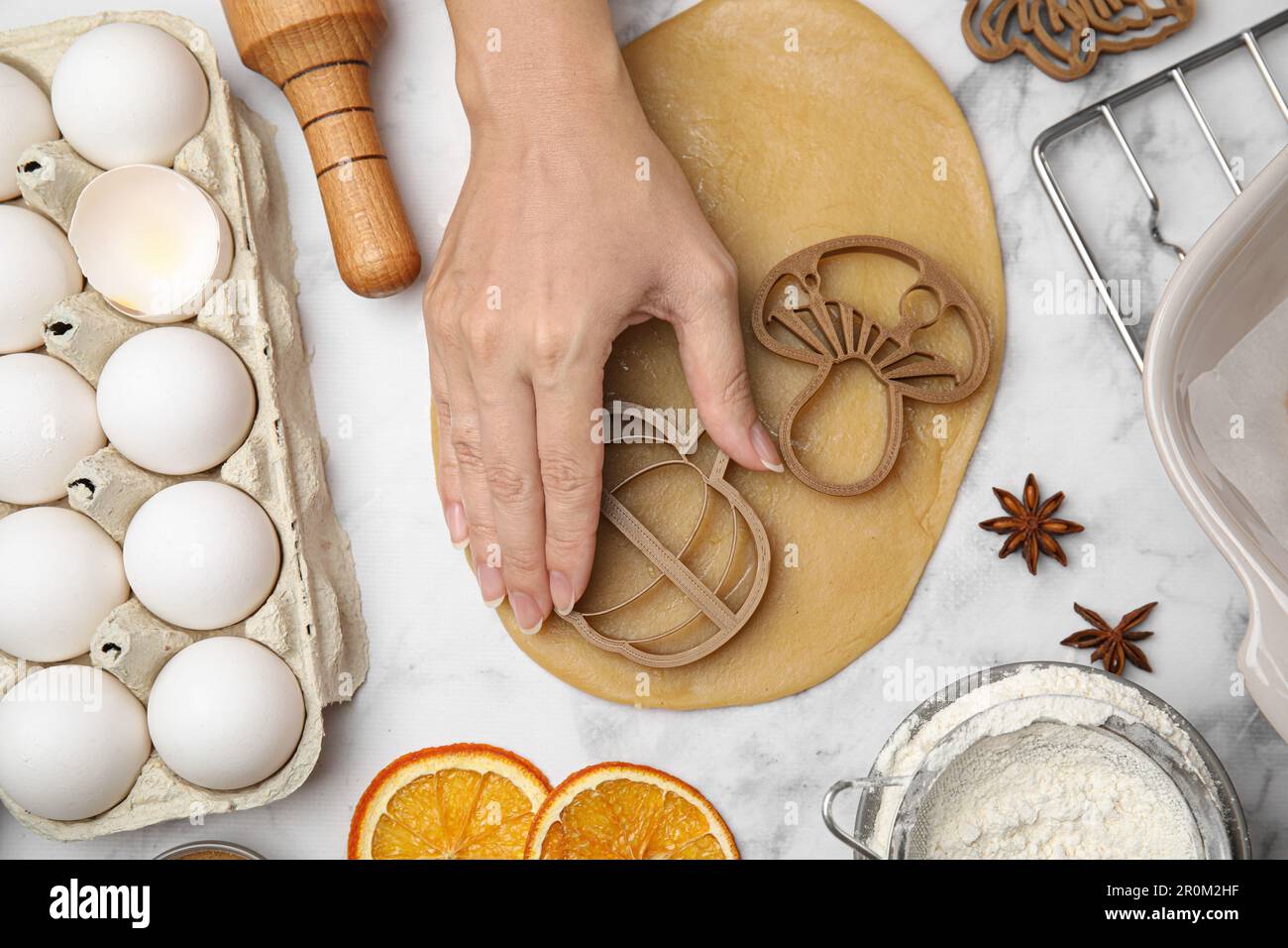 Woman making biscuits with cookie cutters on white marble table, top ...