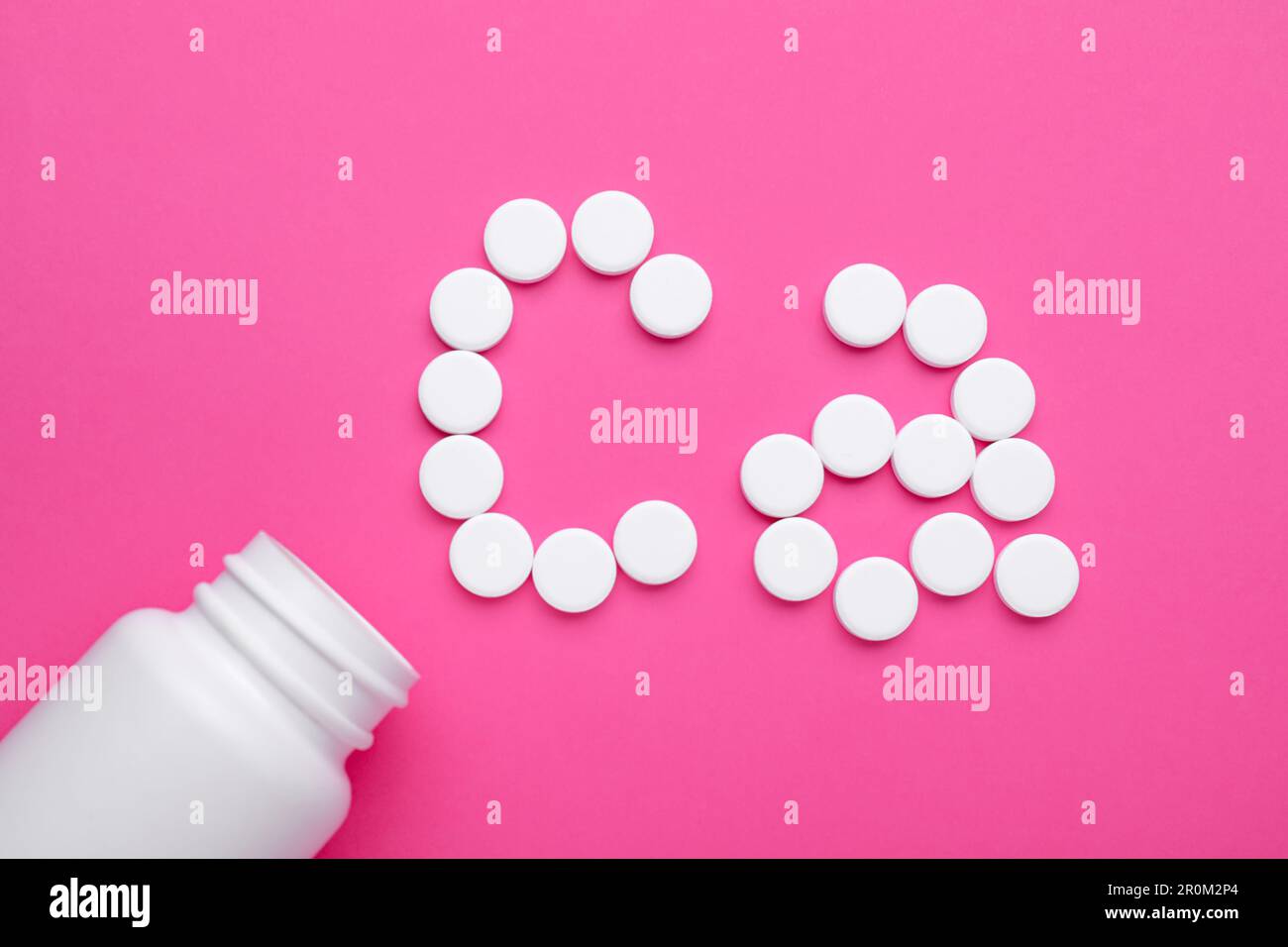 Calcium symbol made of white pills and open bottle on pink background ...