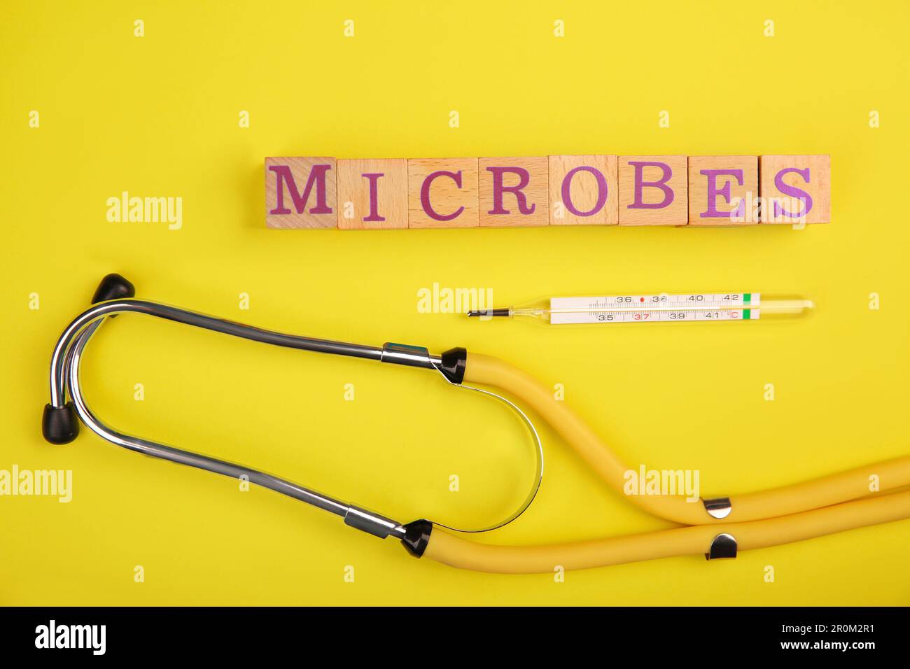 Word Microbes made with wooden cubes, syringe and stethoscope on yellow ...