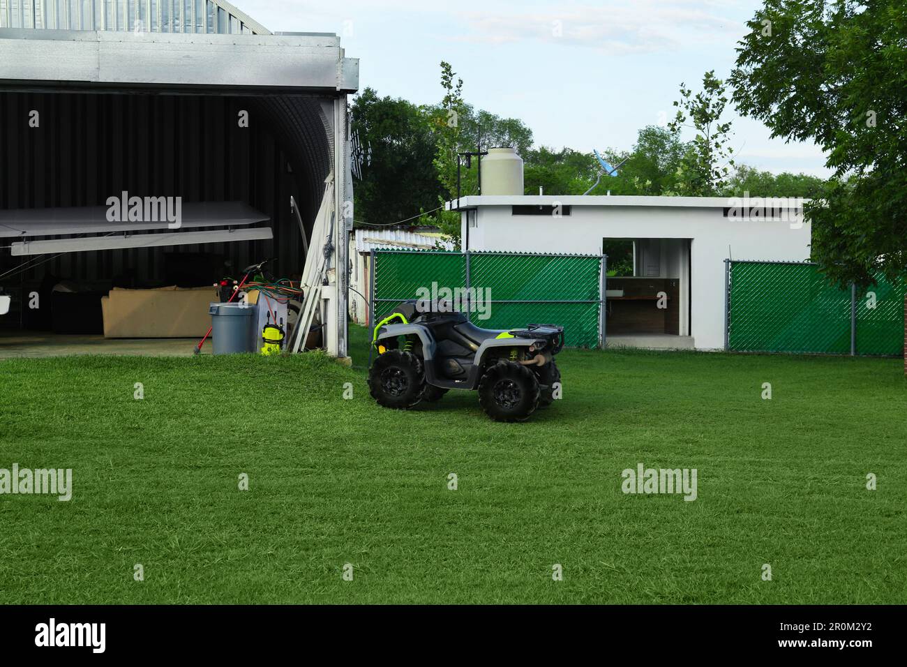 Modern quad bike on green grass and white airplane in big hangar ...
