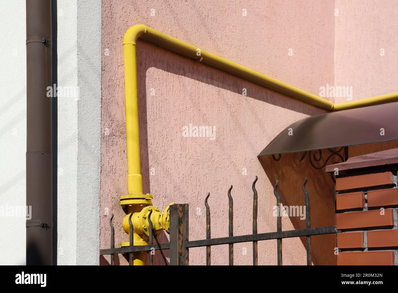 Yellow gas pipe on pink wall outdoors Stock Photo - Alamy