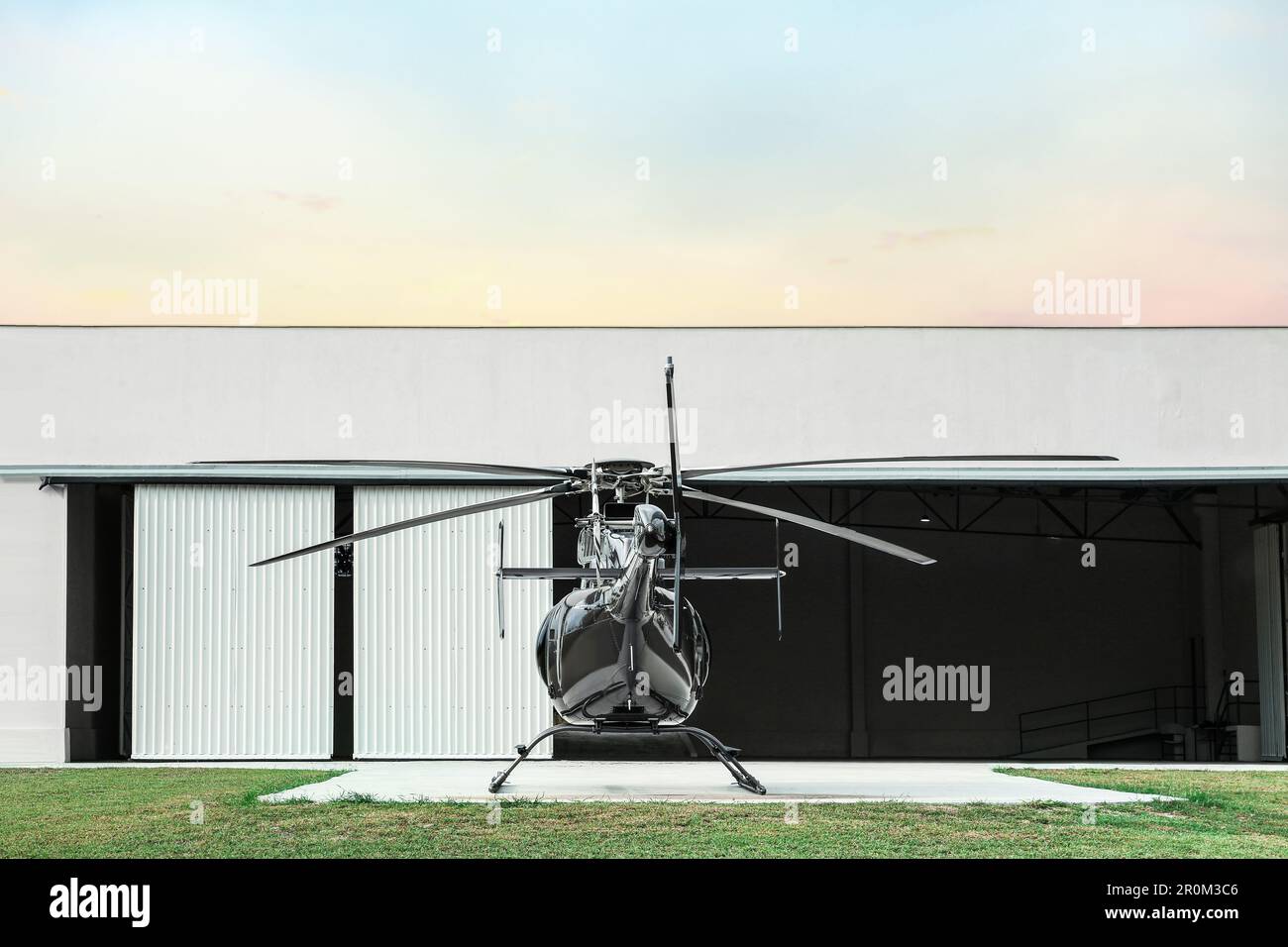 Beautiful helicopter on helipad in field near hangar Stock Photo - Alamy