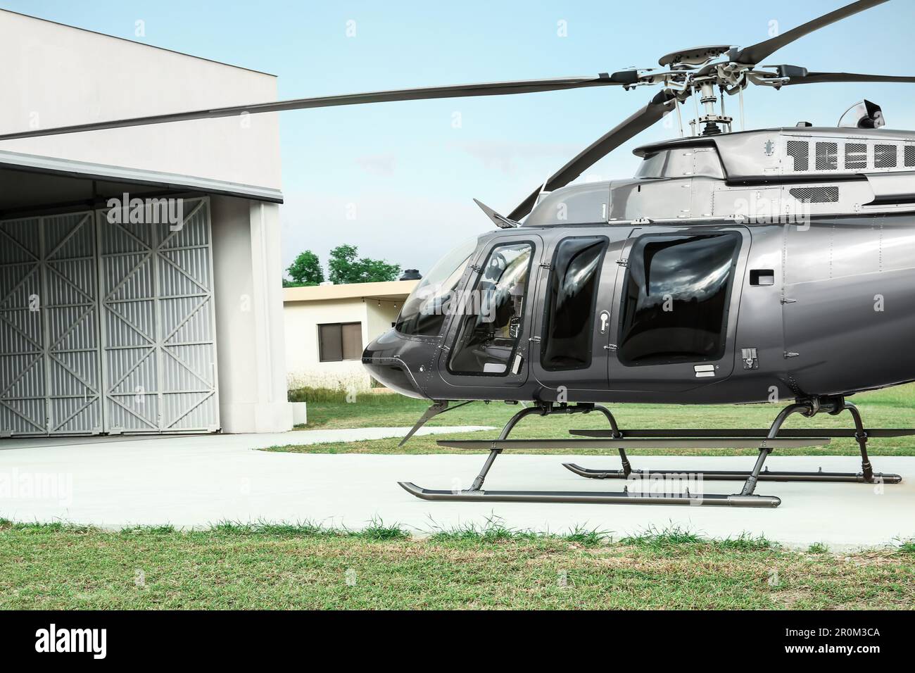 Beautiful helicopter on helipad in field near hangar Stock Photo - Alamy