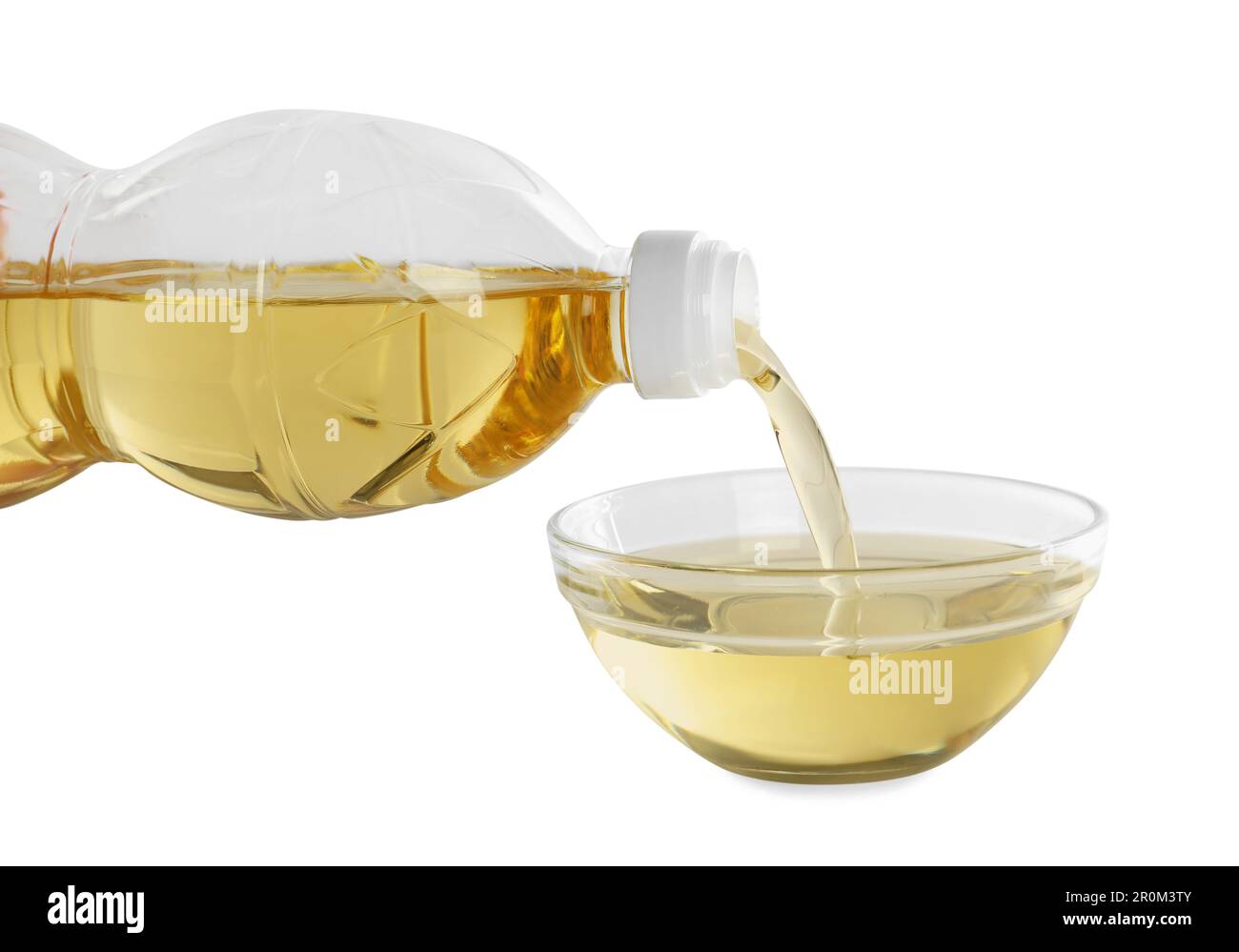 Pouring cooking oil from bottle into bowl on white background, closeup ...