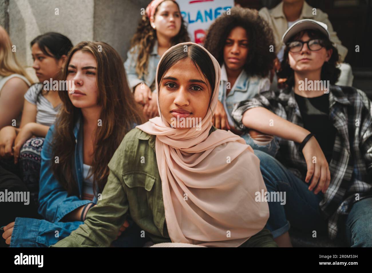 Muslim girl looking at the camera while sitting with a group of climate ...