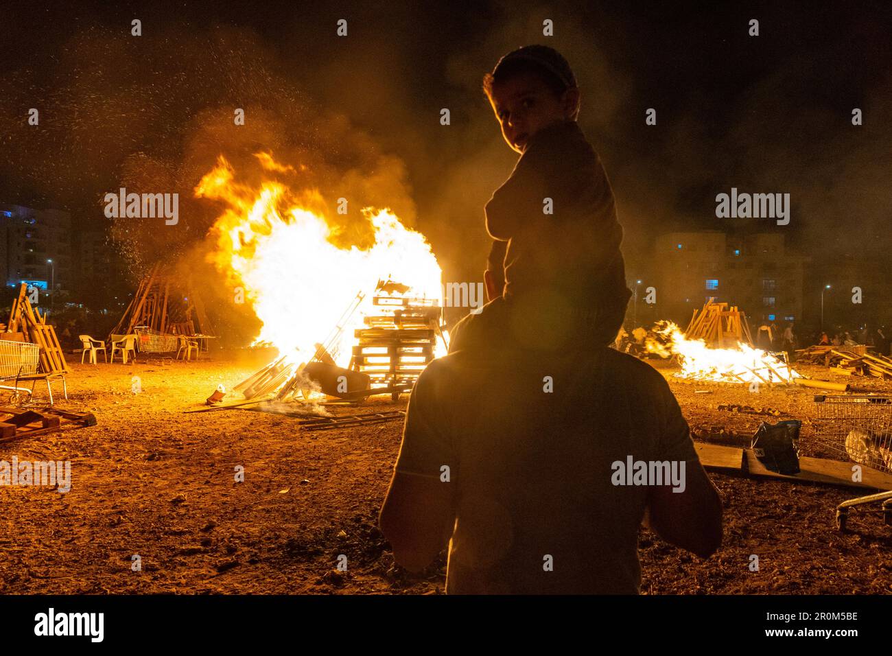 Harish, Israel. A child on his father's shoulders near a fire during ...