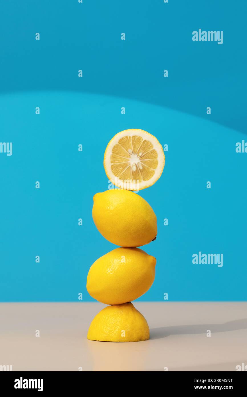 A pyramid of juicy yellow lemons on a blue background. Creative concept ...