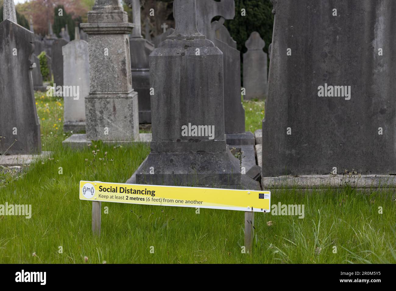 A sign for social distancing next to graves in a cemetery Stock Photo ...