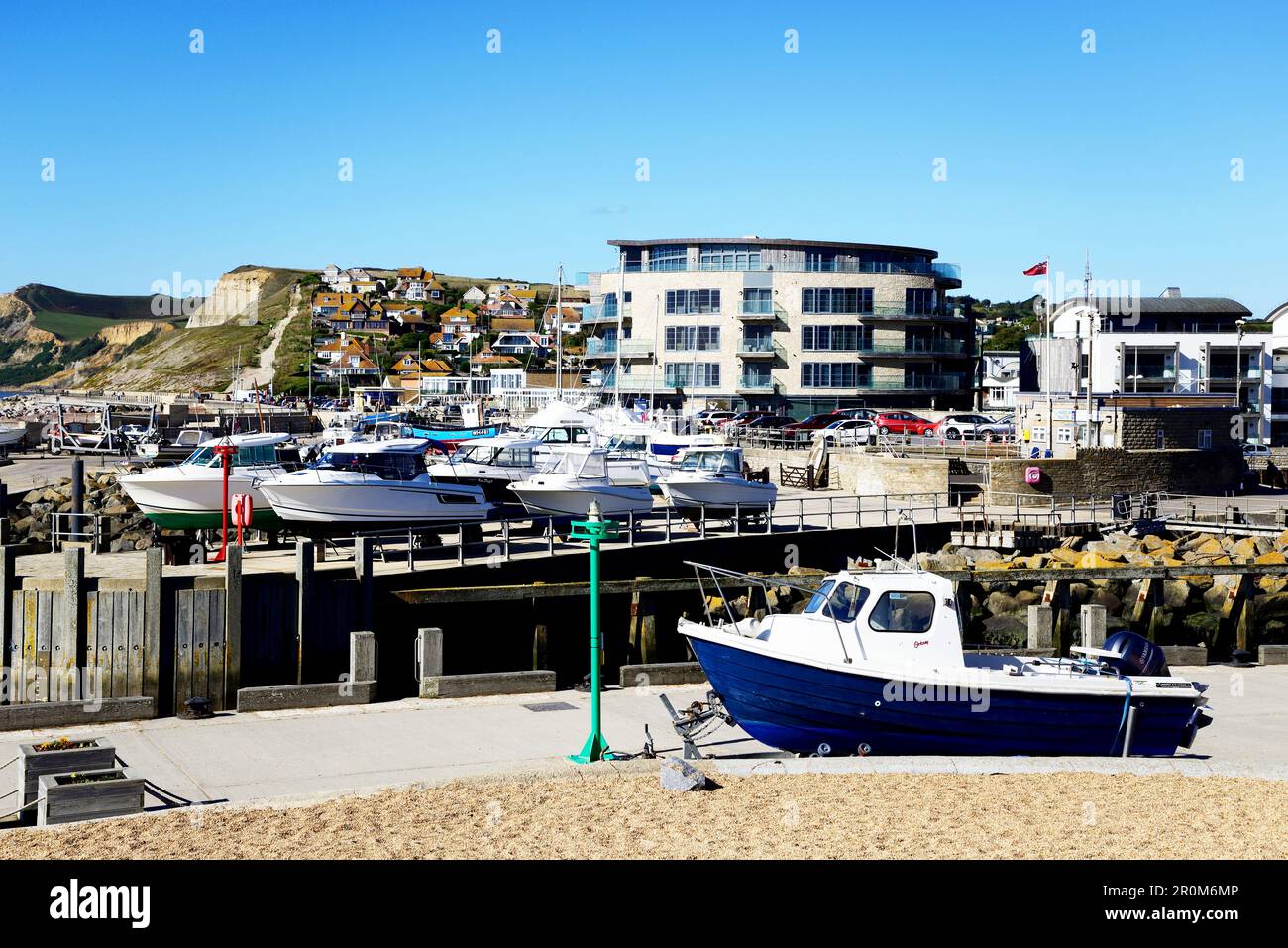 Boats in dry dock with the Ellipse building and along the quayside to the rear, West Bay, Dorset ...