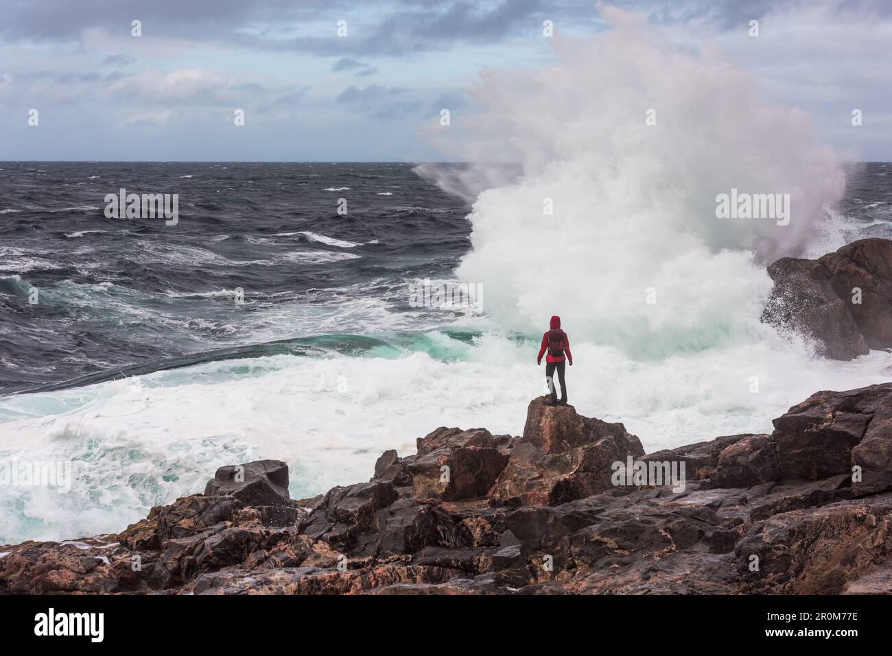 A woman faces the surf of the sea at Sheigra, Highlands, Scotland ...