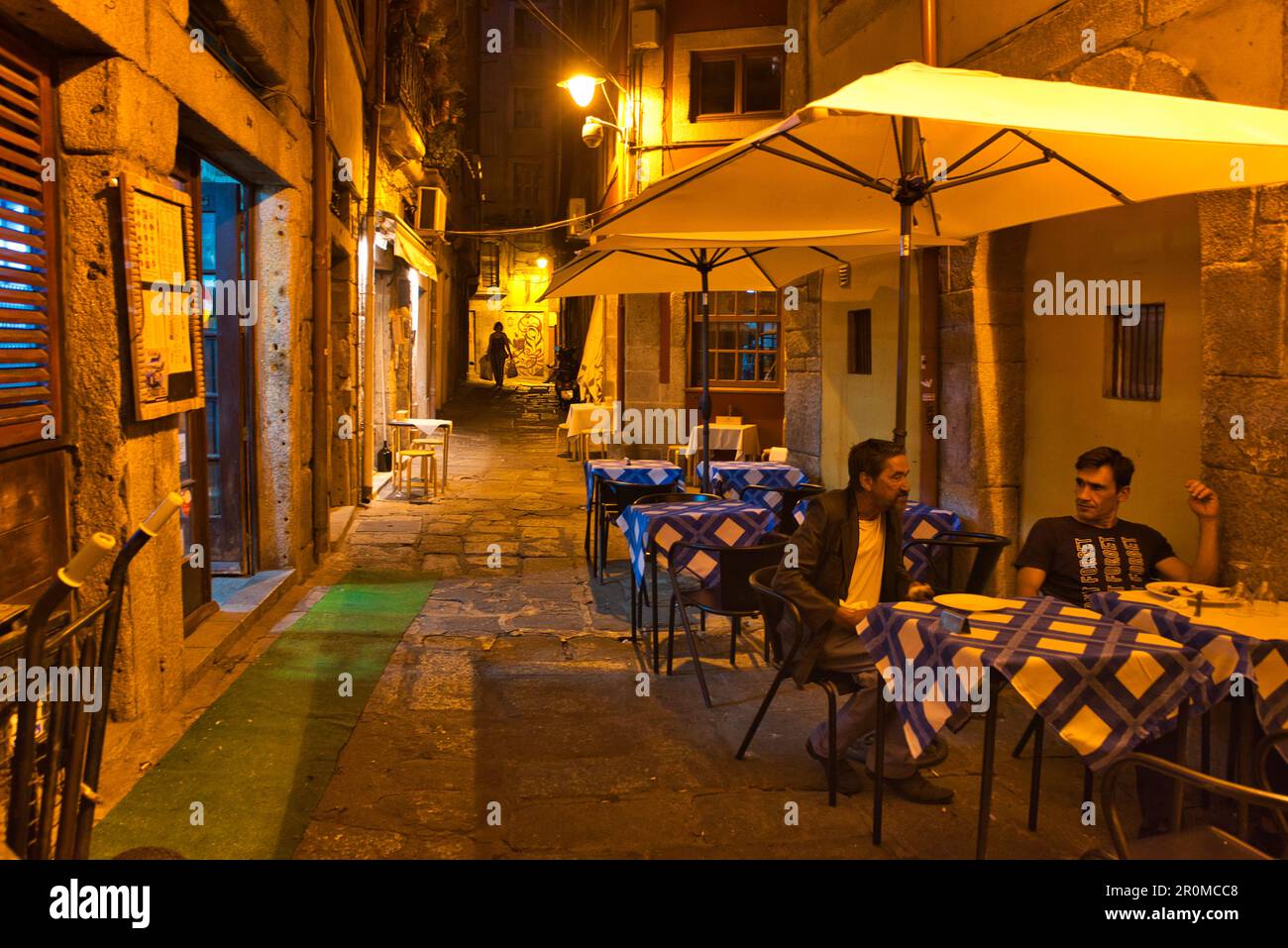 Tables of a small restaurant with two men in the late evening in the ...