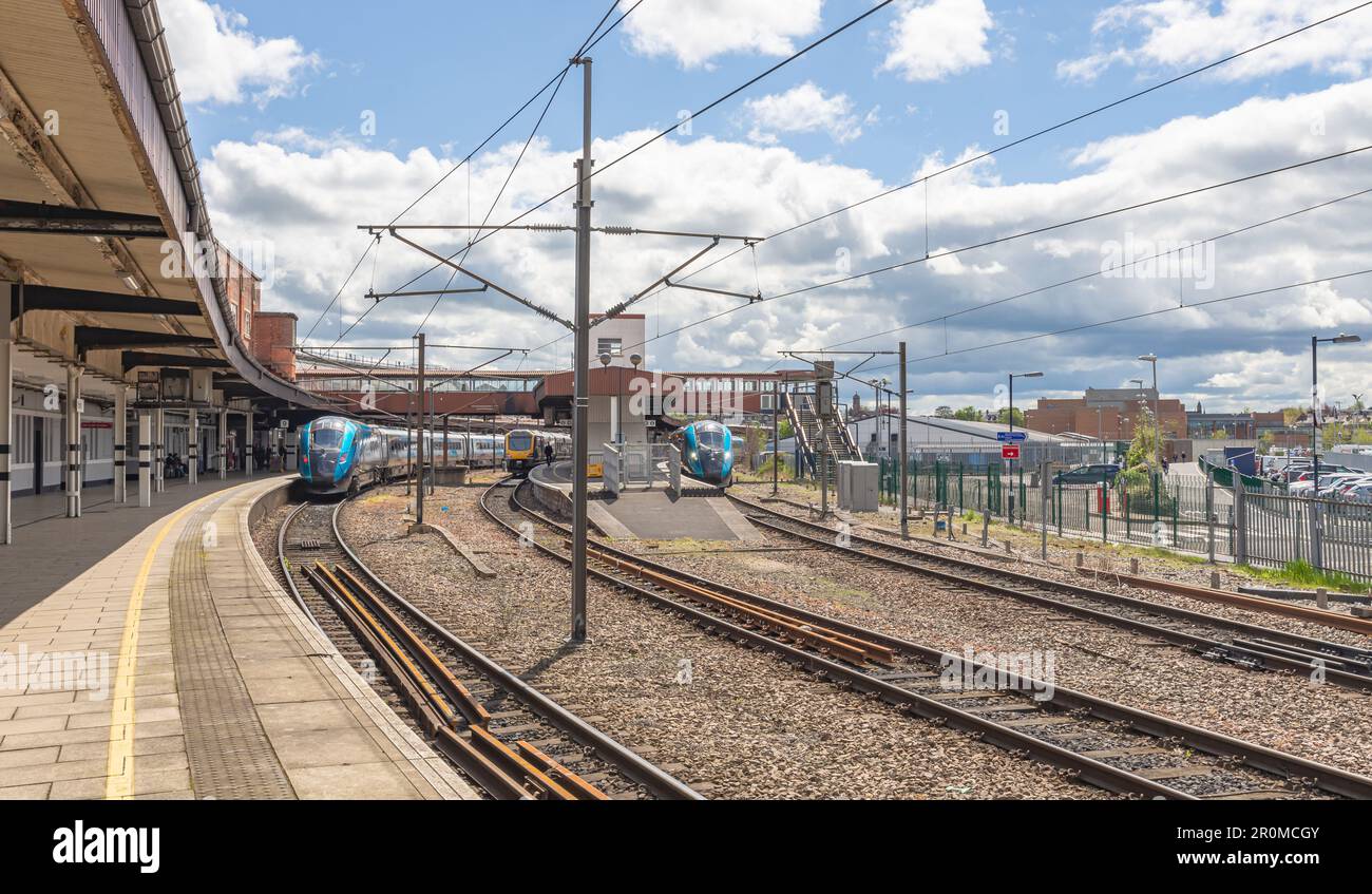 Three trains wait at a railway station. A footbridge connects the ...