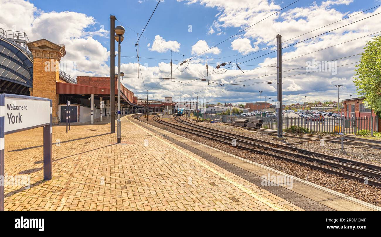 Trains wait at a railway station. A footbridge connects the platforms ...