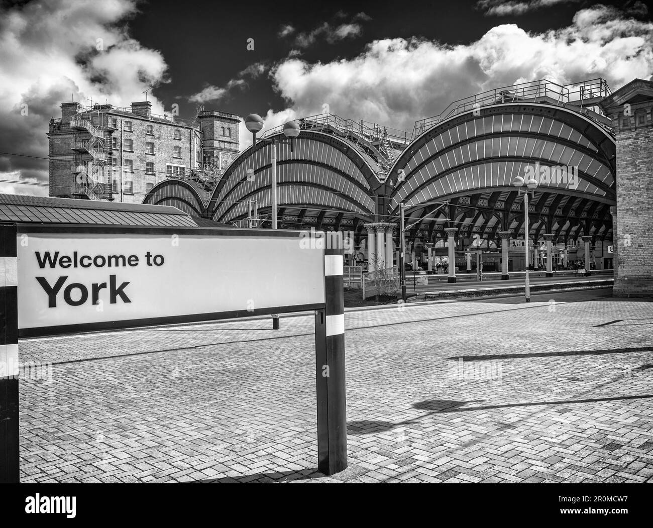 Historic iron and glass arches mark the entrance to a railway station ...