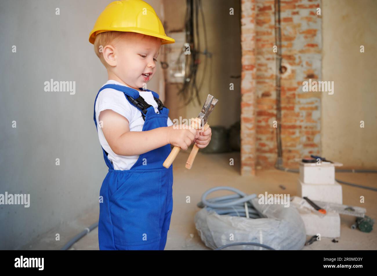 Happy toddler boy looking at instrument in building under construction ...
