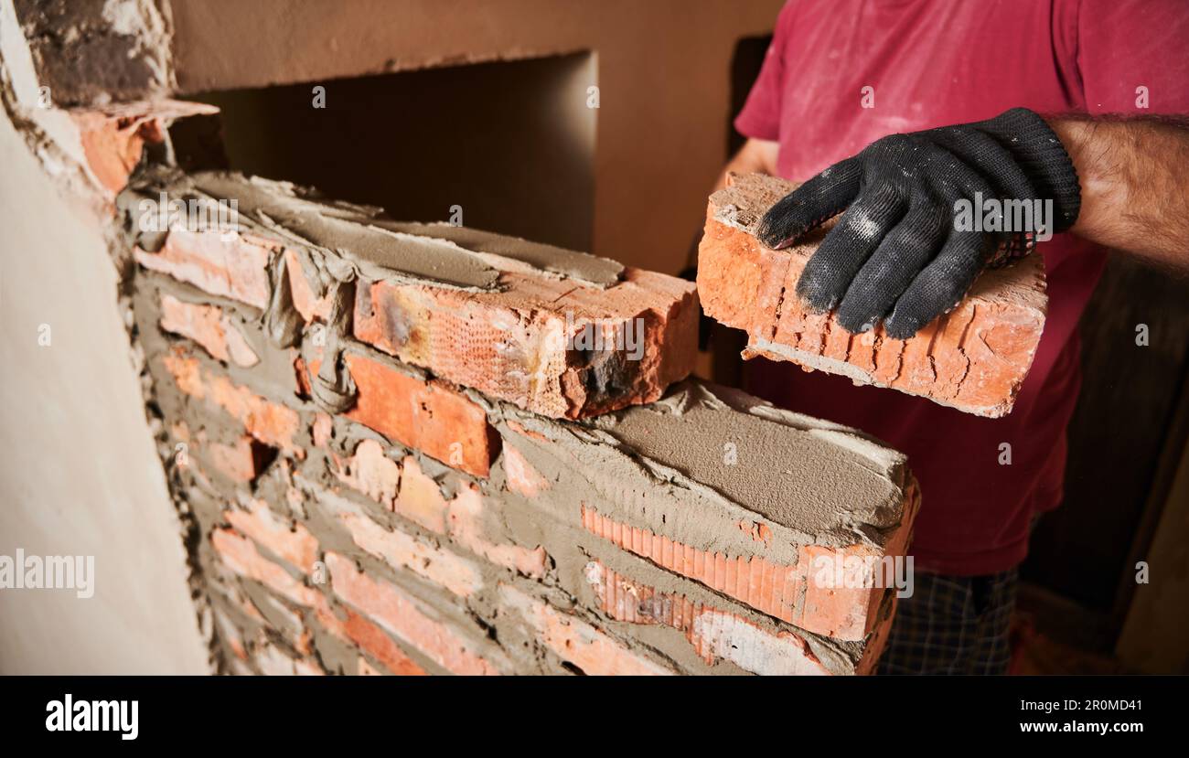 Close up of male hand in work glove laying brickwork in building under ...