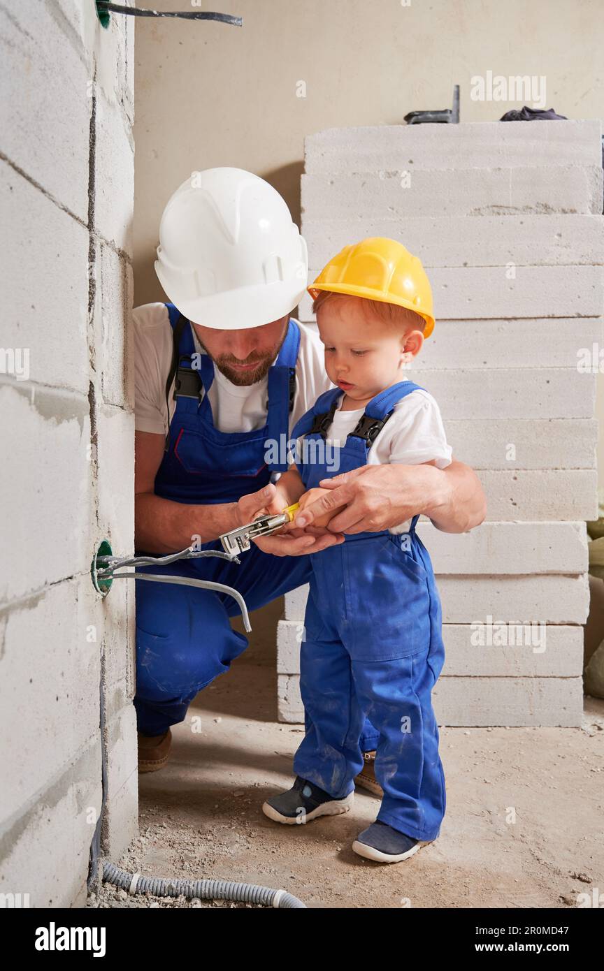 Male worker and child using wire stripper cutter tool while installing ...