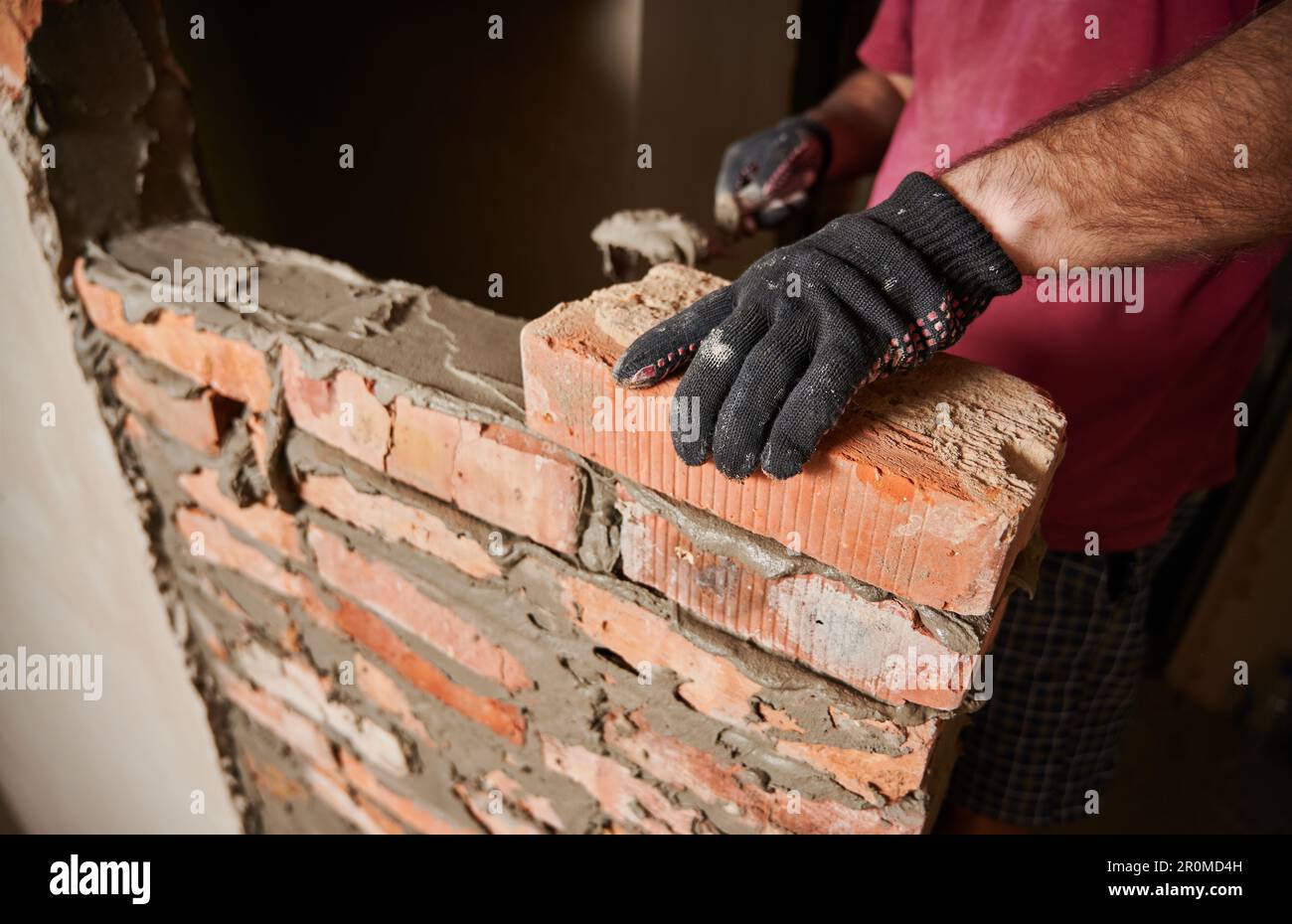 Close up of man hands in work glove laying brickwork in building under ...