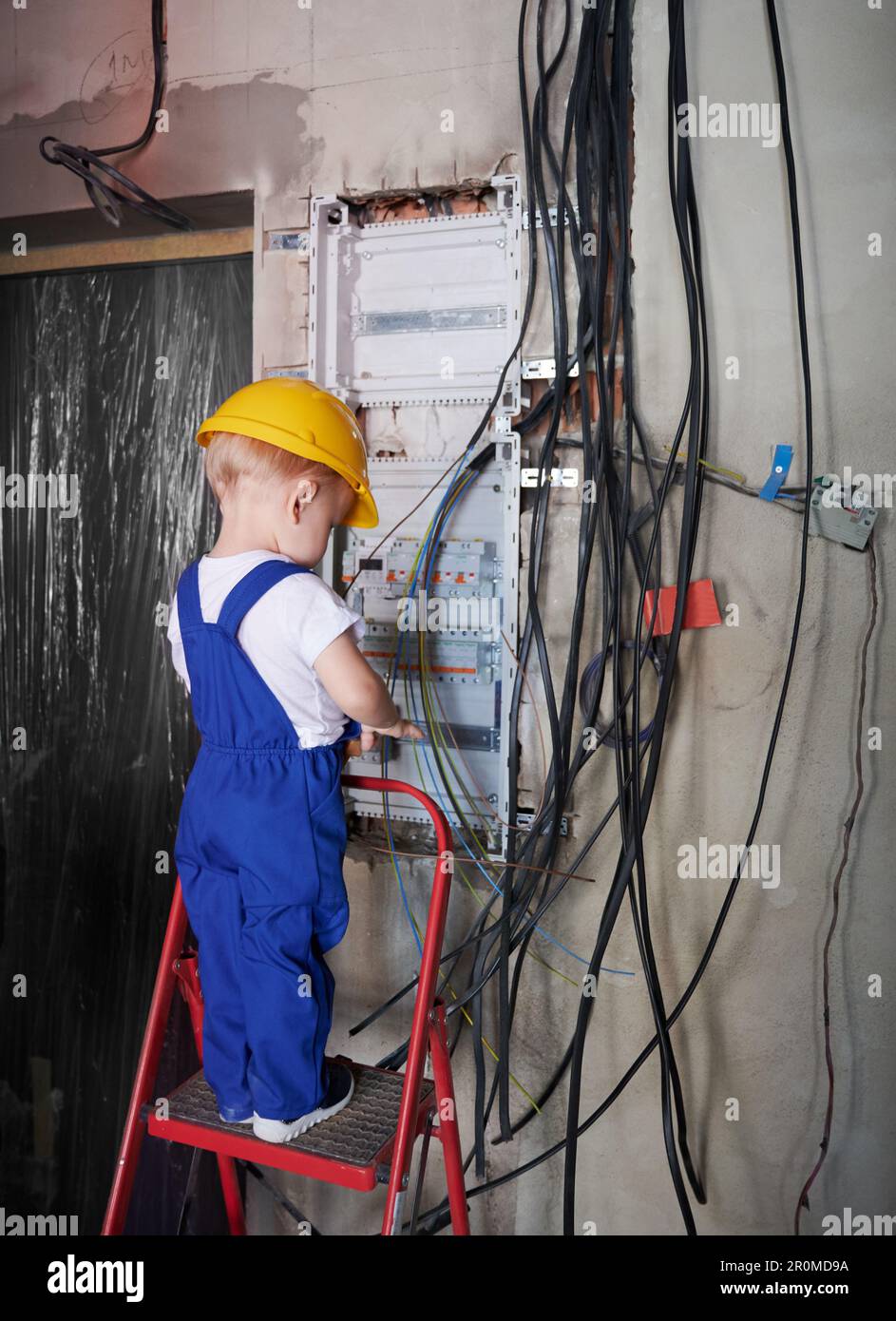 Back view of child electrician standing on ladder near electrical ...