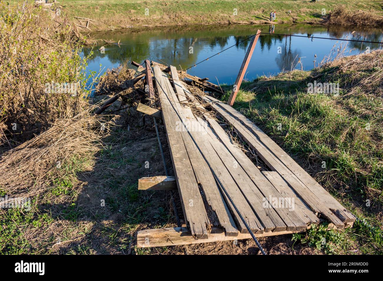 Broken wooden suspension bridge spanning a river in the countryside ...