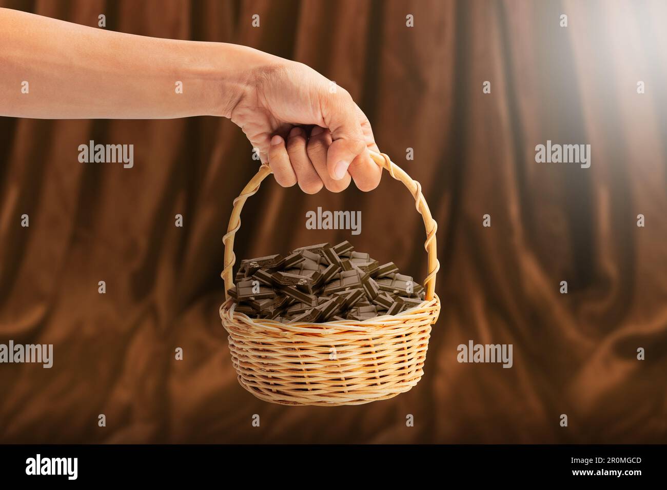 A human hand holding a wooden basket with pieces of chocolate. World ...